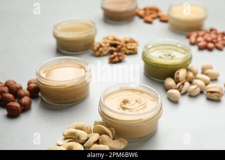 Different types of delicious nut butters and ingredients on white ...