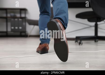 Man tripping over cord in office, closeup Stock Photo - Alamy