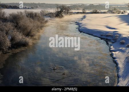 River Whiteadder in early morning light with steam rising from surface ...