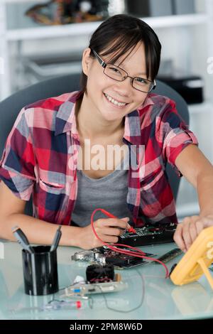 female technician using multimeter and computer and reading ...