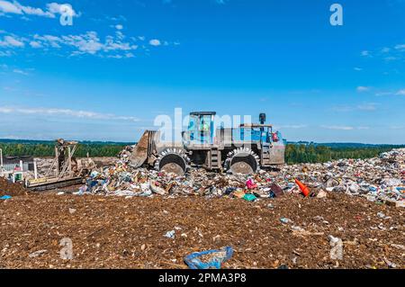 Soil compactors moving around and manipulating trash in the dirt on a ...