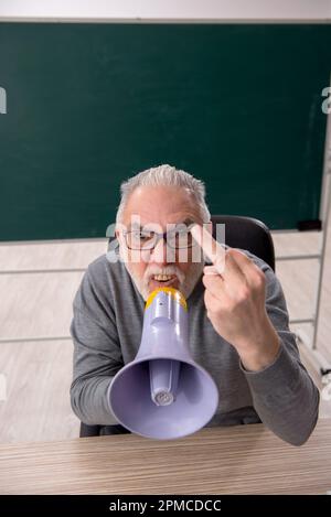 Old teacher holding megaphone in the classroom Stock Photo - Alamy