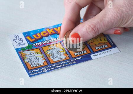 Hand scratching a National Lottery Scratchcard with coin, England, UK ...
