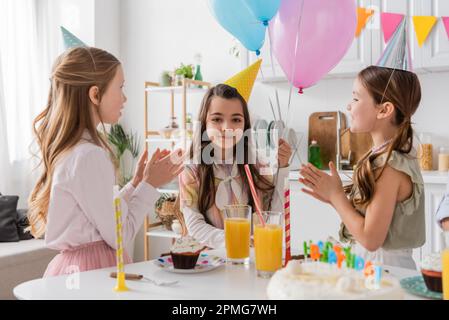 happy kids clapping hands and singing happy birthday song next to cake ...