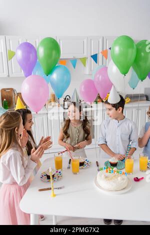 happy kids clapping hands and singing happy birthday song next to cake ...