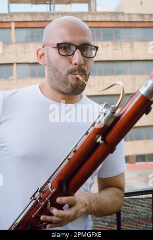 Young bald man playing classical guitar using smartphone at bedroom ...
