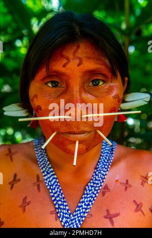 A Yanomami woman with face painting and body decoration holds her child ...