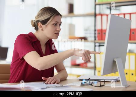 Suspicious woman points finger to screen of computer monitor Stock ...