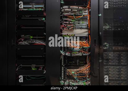 Network and power cables behind racks of computer servers inside a ...