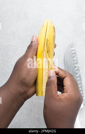 Hands peeling ripe plantains, yellow plantains for frying being peeled ...