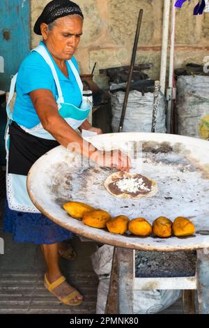 Elder woman making Tlayudas and other specialties in a street food stall, Oaxaca city Mexico ...