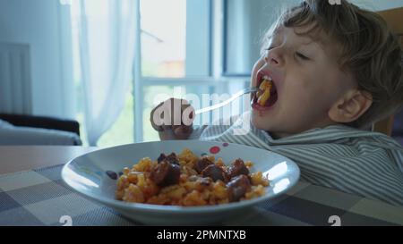 Child eating hot food burning mouth. One small boy spitting pasta out ...