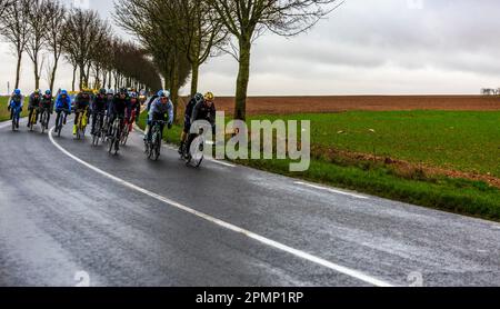 Angerville, France - March 6, 2017: The peloton riding on a wet road ...