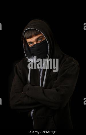 Teenage boy wearing a black mask and black hoodie Stock Photo - Alamy