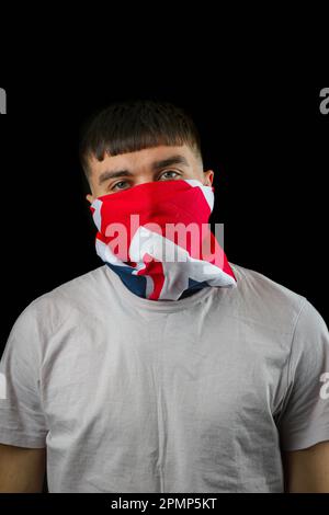 Teenage boy wearing an British flag mask against a black background ...