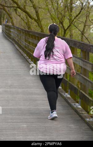 A woman enjoys a spring walk along a walking and biking trail in ...