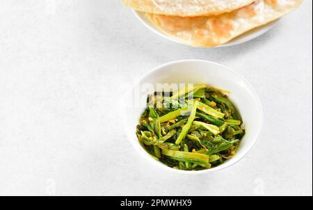Indian style spring onion stir fry in bowl over white background with ...