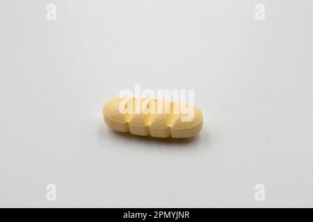 Yellow oblong tablet with dividing strips for dividing into four parts ...