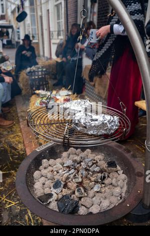 Potato in alumnium foil baked on charcoal barbecue grill outdoor in ...