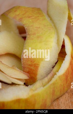 peeled red apple , the peel of a peeled apple scattered on the board ...
