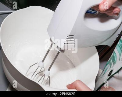Whipping the snow-white confectionery cream with the beaters of an ...