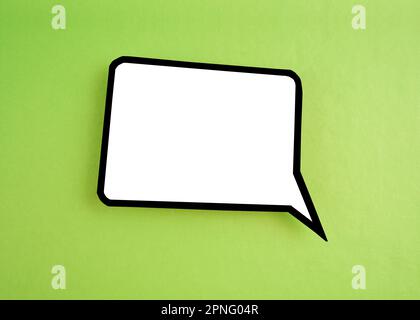 White speech bubble shaped post it note on green background with copy ...