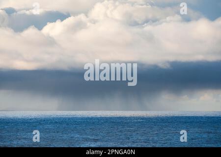 Low-lying rain clouds drift over the open waters of the blue Atlantic ...