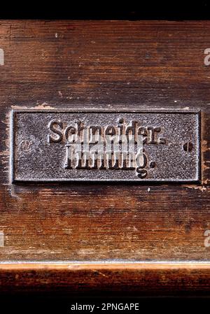 Permanently mounted sign of the tailors' guild on the pew in the ...