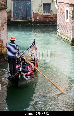 Gondolier with hat on gondola boat in a water canal, Venice, Veneto ...