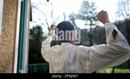 Back of victorious young man raising fist in the air celebrates success ...