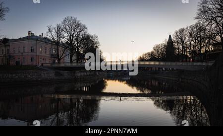 Silhouette of a person walking on Kirjastosilta bridge at dawn in Turku ...