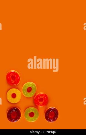 Triangle of round jelly candies at the corner of pink background ...