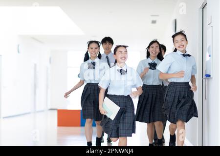 High school students happily running through a summer meadow, holding ...