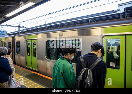 Tokyo rail April 2023, passengers staring at phones wait for a train to ...
