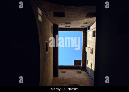 Opening between buildings in a covered alley with a clear sky above ...