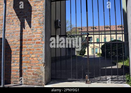 Locked gate and a building at the end of a path in a garden behind it ...