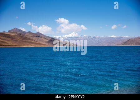 the vibrant lake Yamzho Yumco is surrounded by the Himalayan mountains ...