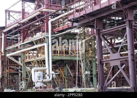 A large iron metal piping trestle with pipes and electric wires and ...