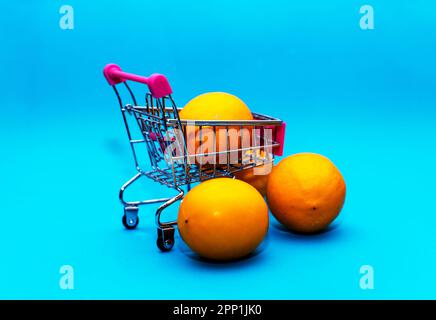Oranges in an iron grocery cart on a blue background. Business and ...