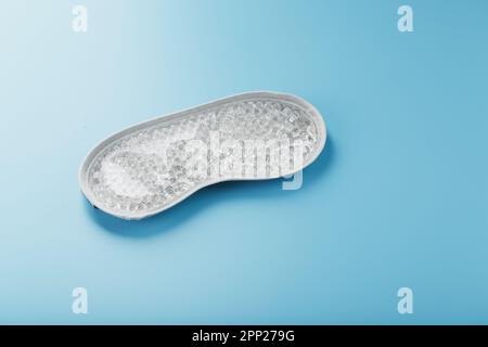 Eye mask with transparent gel balls inside on a blue background. A ...