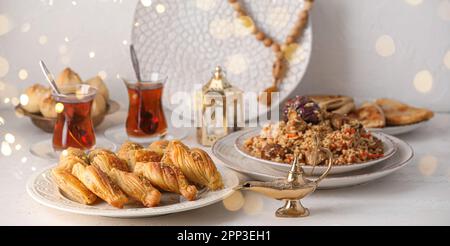 Traditional Eastern dishes with Quran, Aladdin lamp and tasbih on dark ...
