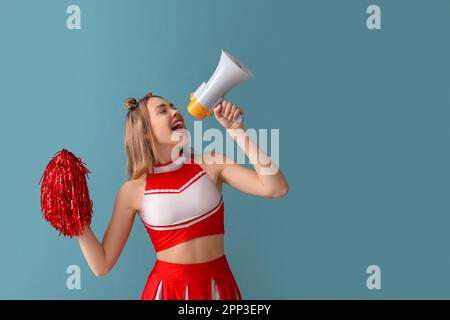 Beautiful cheerleader shouting into megaphone on blue background Stock ...