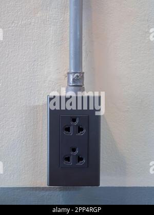 AC power socket, loft style and metal wire pipes on the concrete wall ...