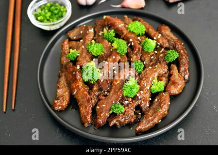 Beef stir-fry with broccoli on black stone background with copy space ...