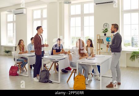 Student answering professor's question standing near his desk in ...