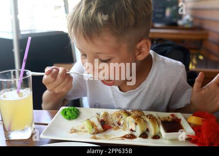 Cute kid boy eating sushi in asian restaurant Stock Photo - Alamy