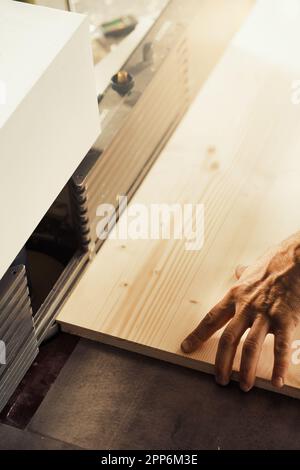 Strong carpenter's hands hold, guide, restrain, push, and move lumber ...