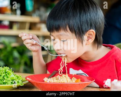 Happy Asian boy eating delicious noodle Stock Photo - Alamy