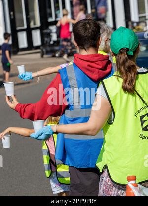 At a 10k road race helpers hold out plastic cups of water for the ...