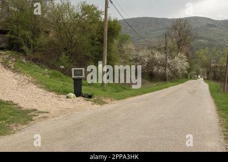 Discarded TV on top of trash can at countryside road Stock Photo - Alamy